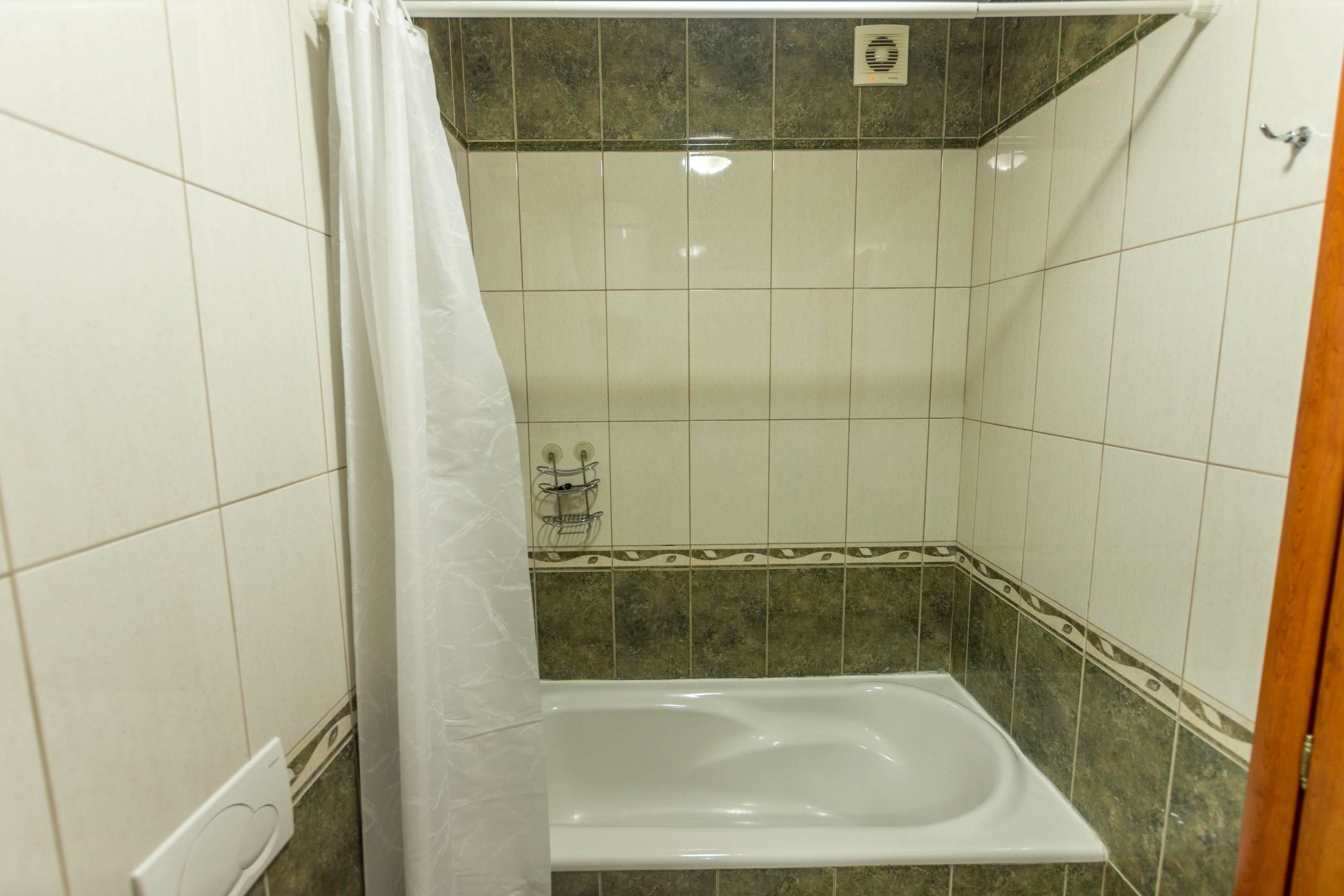 Casa de banho com banheira, paredes revestidas a azulejos e cortina de chuveiro.