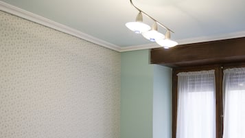 Um quarto pequeno e simples, com duas camas, uma escrivaninha e uma cadeira.