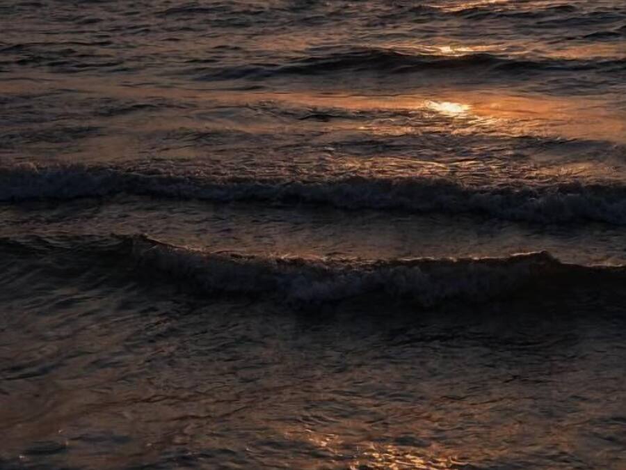Um pôr do sol sobre o oceano, com ondas refletindo a luz do sol.