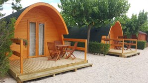 Duas cabanas de madeira com telhados curvos, cada uma com um deck de madeira, uma mesa e cadeiras.