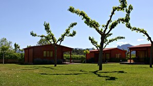 Um edifício com fachada vermelha, rodeado por um espaço gramado com árvores.