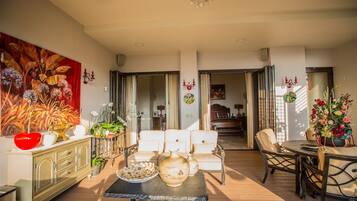Uma sala ampla com um conjunto de sofás, uma mesa de jantar e um quadro grande na parede.