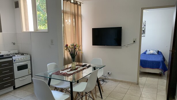 Um espaço de estar compacto com cozinha, área de refeições e um quarto.