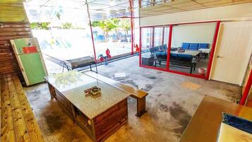 Um quarto amplo com piso de madeira, um balcão central espaçoso e vista para o exterior por grandes janelas.