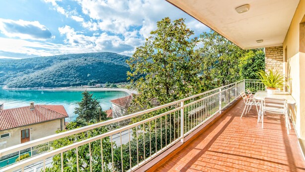 Uma varanda com vista para a costa, incluindo praia e montanhas.