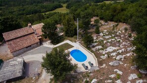 Uma casa com telhado de cerâmica, piscina e um pátio de pedra.
