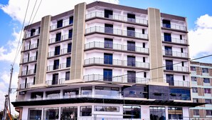 Um edifício com vários andares, varandas, entrada coberta e área comercial no térreo.