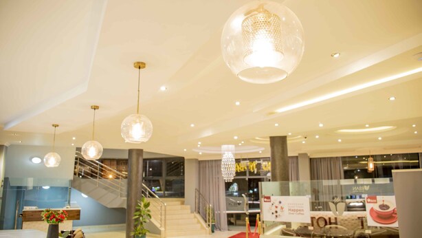 Um hall de hotel moderno com escada, balcão de recepção e um bar de café.