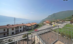 Uma cidade costeira com edifícios voltados para o mar, uma área de estacionamento e vista para montanhas distantes.