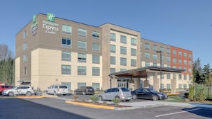Edifício do Holiday Inn Express com estacionamento e vários carros.