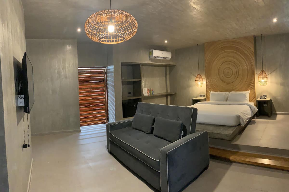 Quarto moderno com sofá, cama e parede decorativa de madeira.