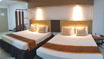 Quarto de hotel com duas camas, cada uma com cabeceira, mesa de cabeceira e telefone.