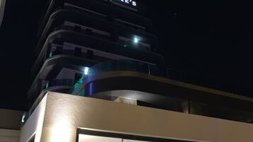 Um hotel chamado "Khal Suite's", com design arquitetônico moderno, vários andares e uma placa iluminada de destaque.