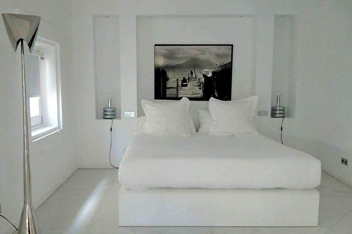 Um quarto moderno com uma cama grande, um abajur e um quadro na parede.