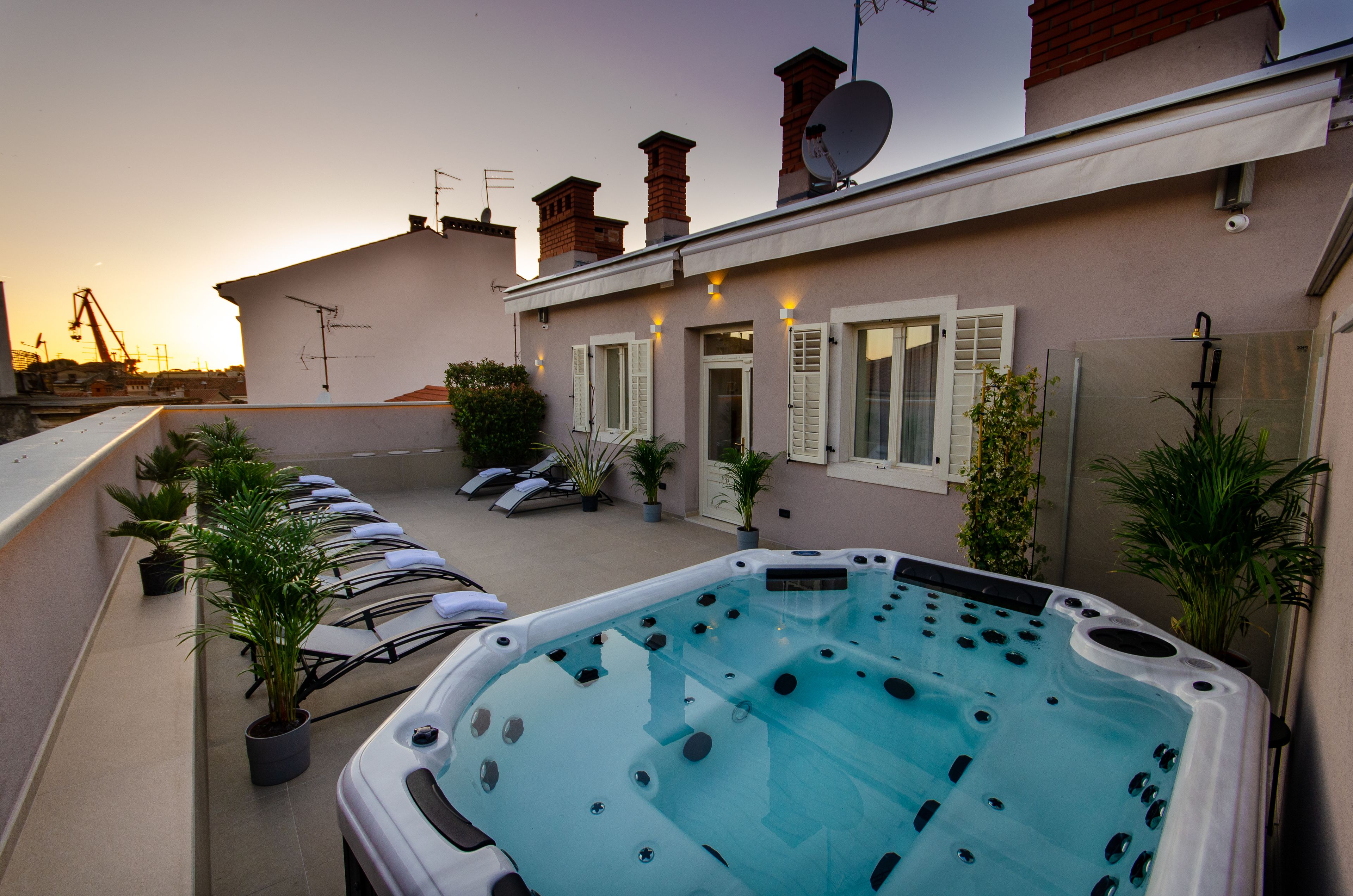 Uma área de piscina no terraço com espreguiçadeiras e plantas em vasos.