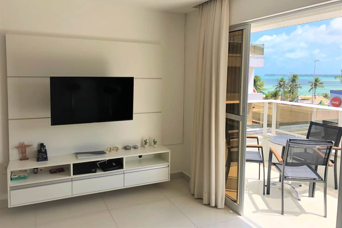 Apartamento superior, 1 quarto, sacada, vista para o mar | Área de estar | TV de tela plana