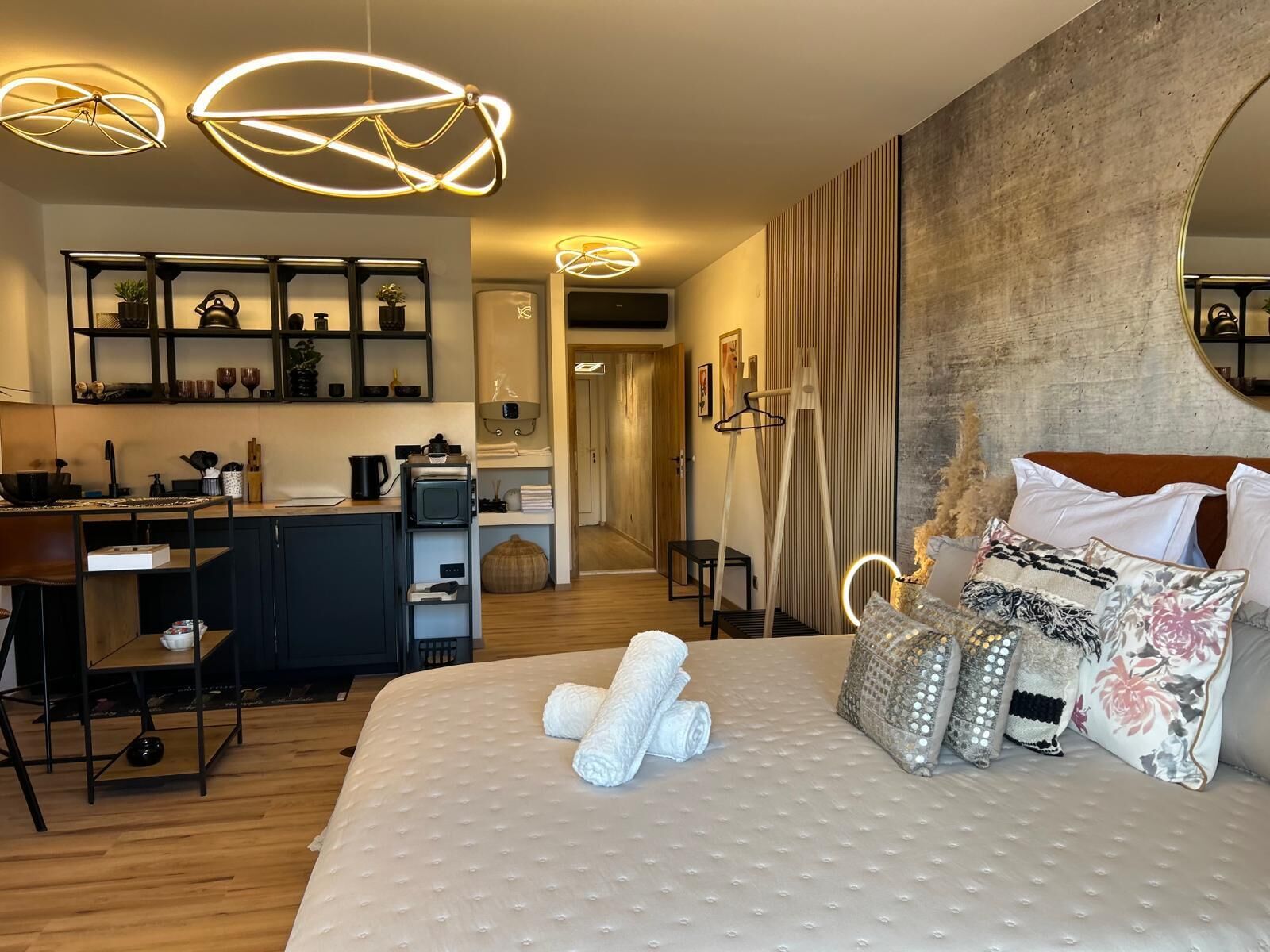 Quarto de hotel moderno com uma cama grande, uma kitchenette e um espaço de refeições.