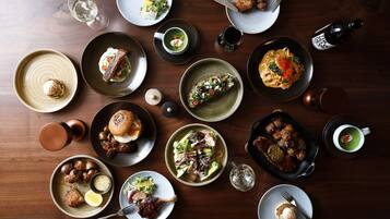 Diversos pratos e bebidas sobre uma mesa de madeira, indicando um ambiente de refeições.