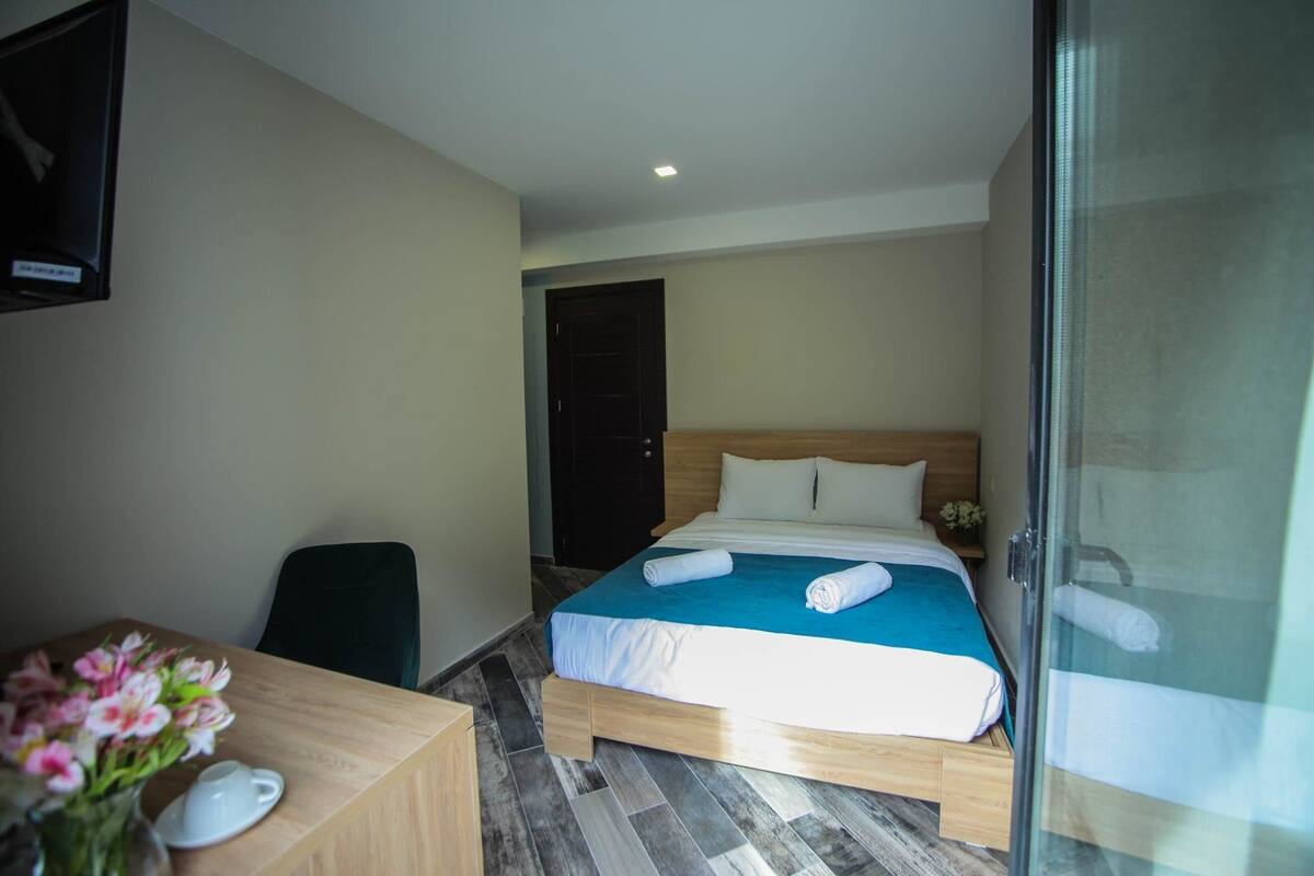 Quarto de hotel com cama, escrivaninha e cadeira.