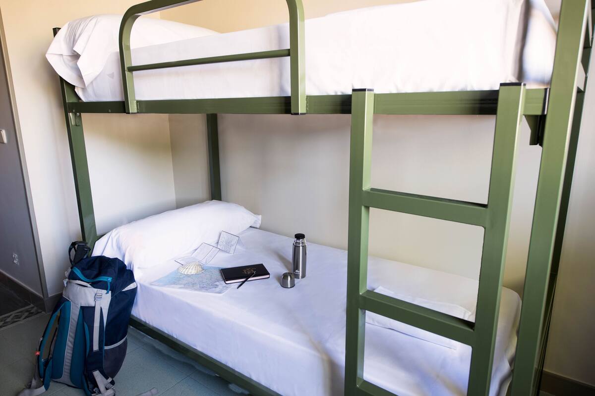 Uma cama beliche com uma mochila e uma garrafa térmica na cama de baixo.