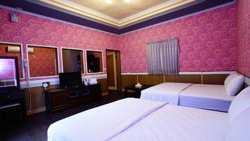 Quarto de hotel com duas camas, televisão, escrivaninha e espelho.