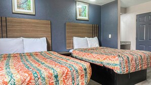 Quarto de hotel com duas camas, cada uma com colcha estampada, cabeceiras de madeira e quadros nas paredes.
