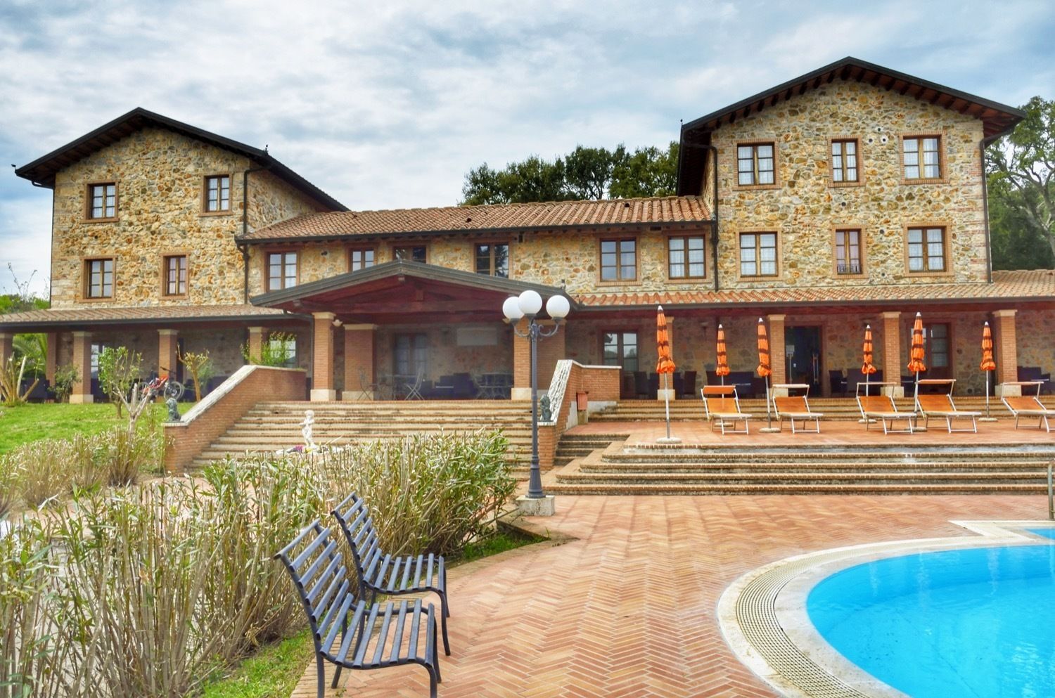 Um edifício de pedra com piscina, área de estar externa e um terraço coberto.