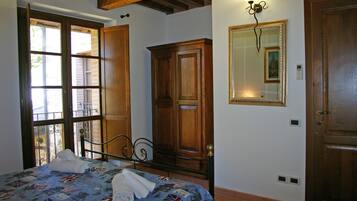 Quarto com cama, guarda-roupa de madeira e espelho na parede.
