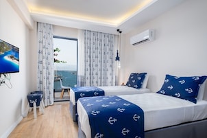 Quarto de hotel com duas camas, televisão, varanda e vista para o mar, além de ar condicionado.