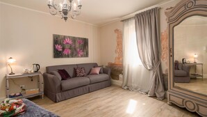 Uma sala de estar aconchegante com um sofá, uma mesa de centro, um abajur e um quadro com flores.