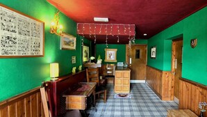 Um restaurante com paredes verdes, bancos de madeira e chão quadriculado.