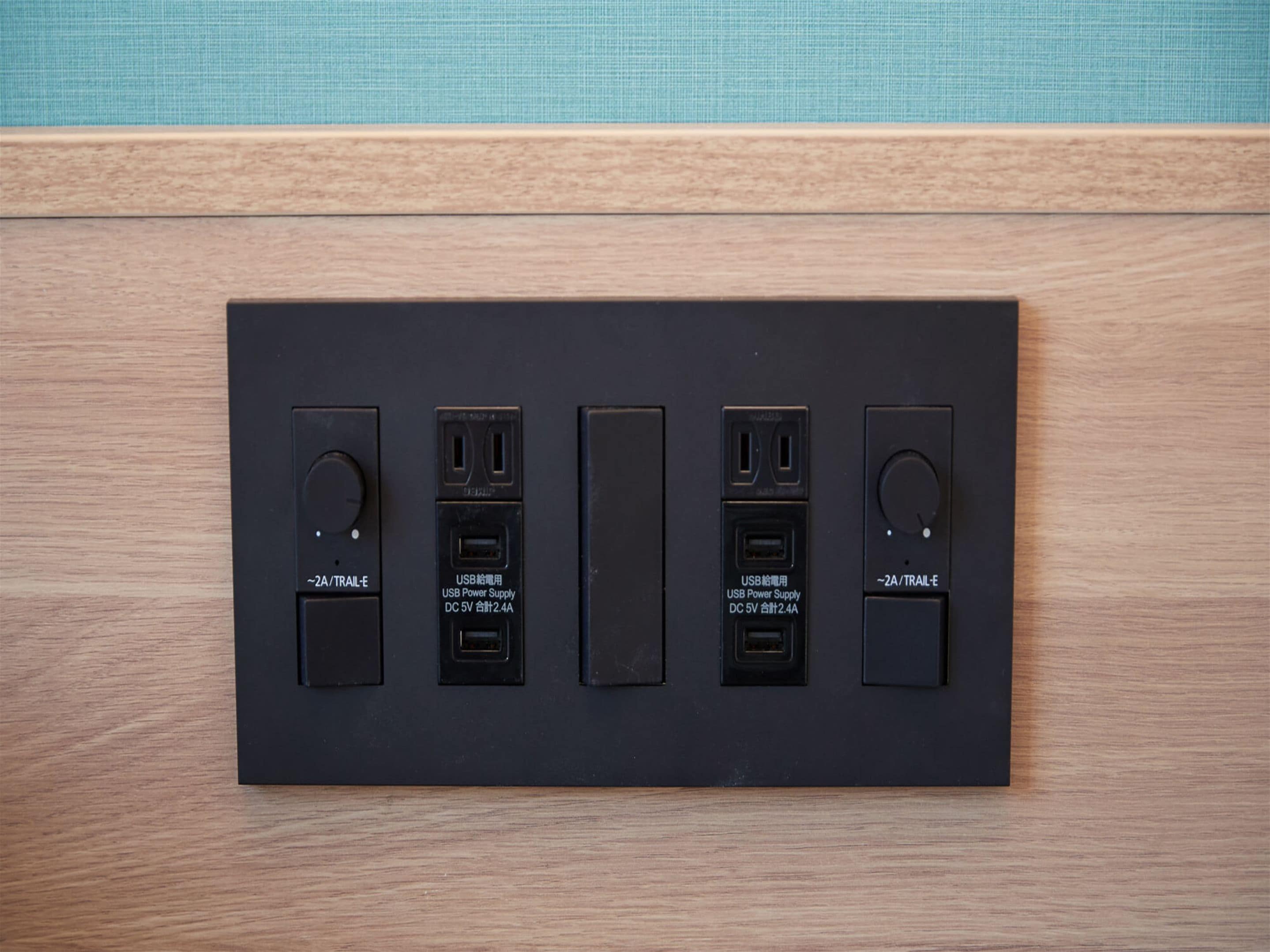 Um quadro elétrico preto com várias portas USB e uma tomada em uma superfície de madeira.