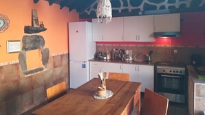 Cozinha com armários brancos, uma mesa de jantar de madeira e um lustre.