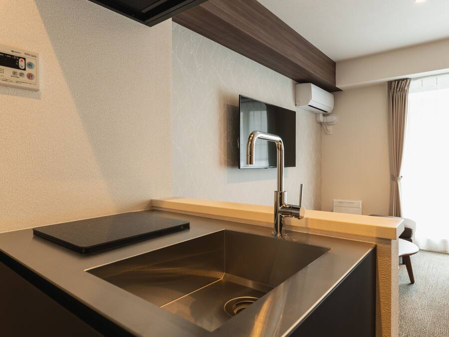 Uma cozinha moderna com pia de aço inoxidável, forno embutido e televisão de tela plana fixada na parede.