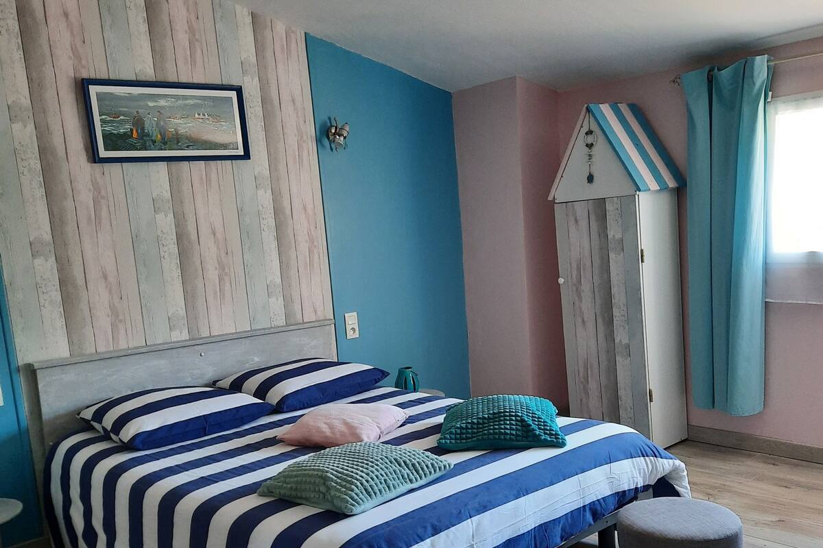 Quarto com cama, dois banquinhos, cômoda e um quadro na parede.
