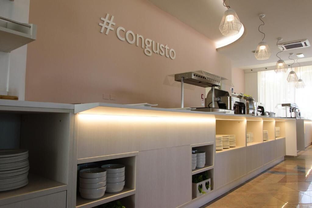 Uma cozinha moderna com um letreiro #congusto, uma cafeteira e pratos e tigelas organizados em prateleiras.