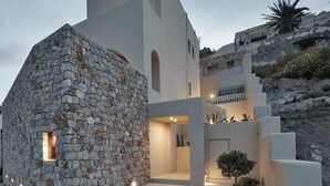 Um edifício moderno com fachada de pedra, varanda e um pequeno jardim.
