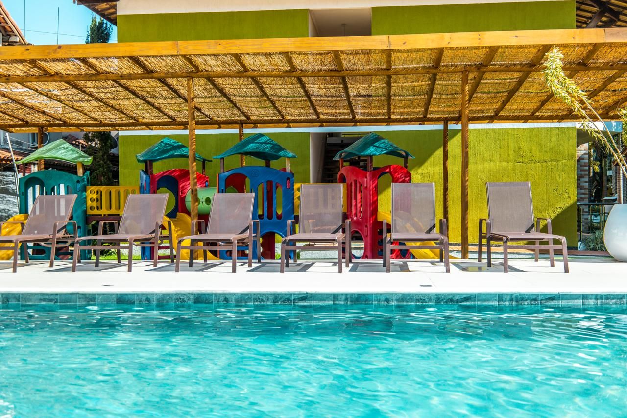 Uma área de piscina com espreguiçadeiras e estruturas coloridas para brincar.