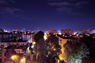 Paisagem urbana noturna com edifícios e árvores iluminados.