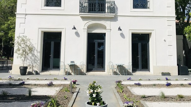 Um edifício de dois andares com fachada simétrica, janelas amplas e uma entrada central.