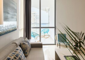 Uma sala de estar moderna com sofá, mesa de centro e vista para uma varanda com cadeiras.