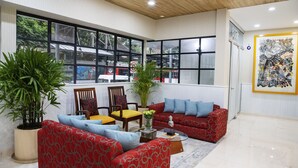 Uma sala de estar moderna com sofás estampados em vermelho, uma mesa de centro de vidro e grandes janelas com vista para a rua.