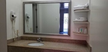 Um secador de cabelo, toalhas fornecidas, sabão, champô