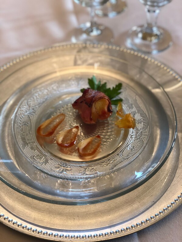 Uma fatia de comida guarnecida com salsa, em um prato de vidro transparente com borda decorativa.