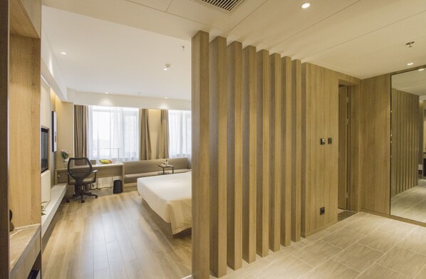 Quarto de hotel moderno com uma cama grande, uma mesa, uma cadeira e uma televisão.