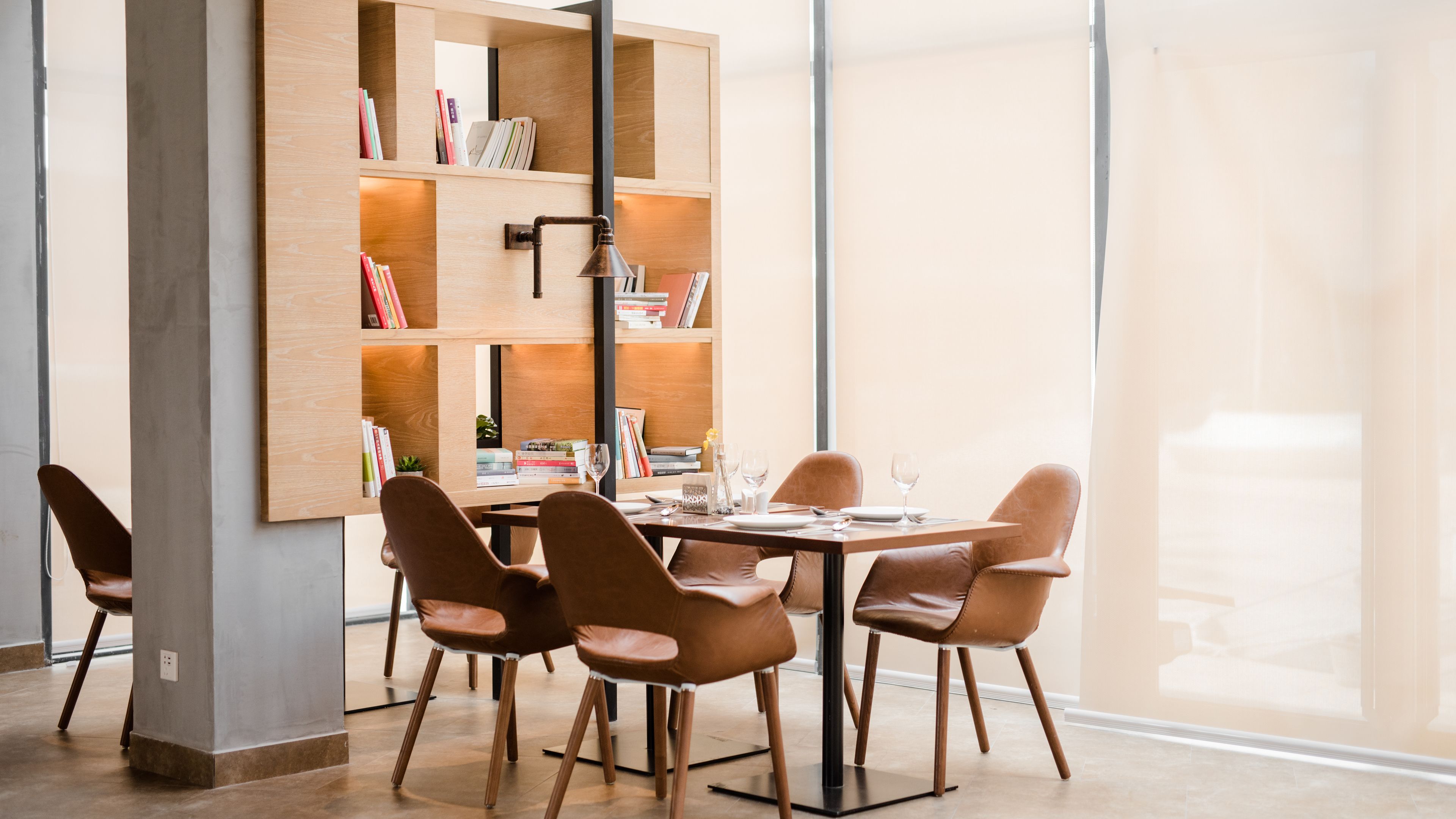 Uma sala de jantar moderna com estante de madeira, cadeiras de couro e mesa de vidro posta para refeições.