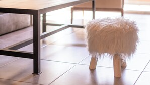 Uma sala de estar moderna com um sofá, uma poltrona, uma mesa e um banquinho macio.