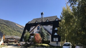 Um edifício de dois andares com telhado inclinado, chaminé e uma pequena varanda.