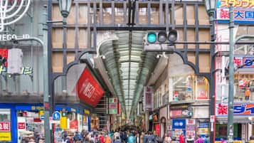 Uma rua urbana movimentada com várias lojas e placas, incluindo uma loja MEGO bem visível.