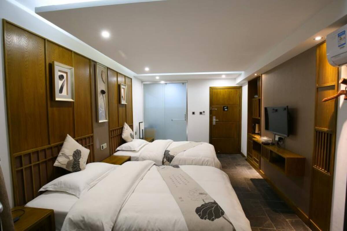 Quarto de hotel com duas camas, televisão e guarda-roupa.